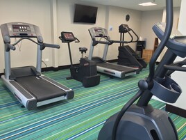 Centro de fitness com esteiras, bicicleta ergométrica e remo.