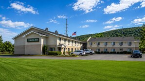 Um hotel com uma placa indicando 'CORNING INN', um estacionamento com vários carros e montanhas ao fundo.