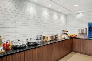 Cozinha moderna com azulejos brancos tipo metrô, bancada preta e diversos dispensadores de alimentos.