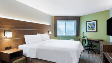 Quarto de hotel com uma cama grande, uma escrivaninha, uma cadeira e uma televisão.