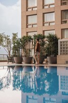 Um homem passeando perto de uma piscina com grandes vasos e um edifício ao fundo.