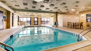 Piscina interna com água cristalina, paredes azulejadas e teto com grelhas quadradas.
