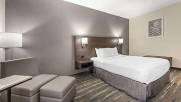 Quarto de hotel com uma cama grande, uma escrivaninha, uma cadeira e uma pequena mesa.