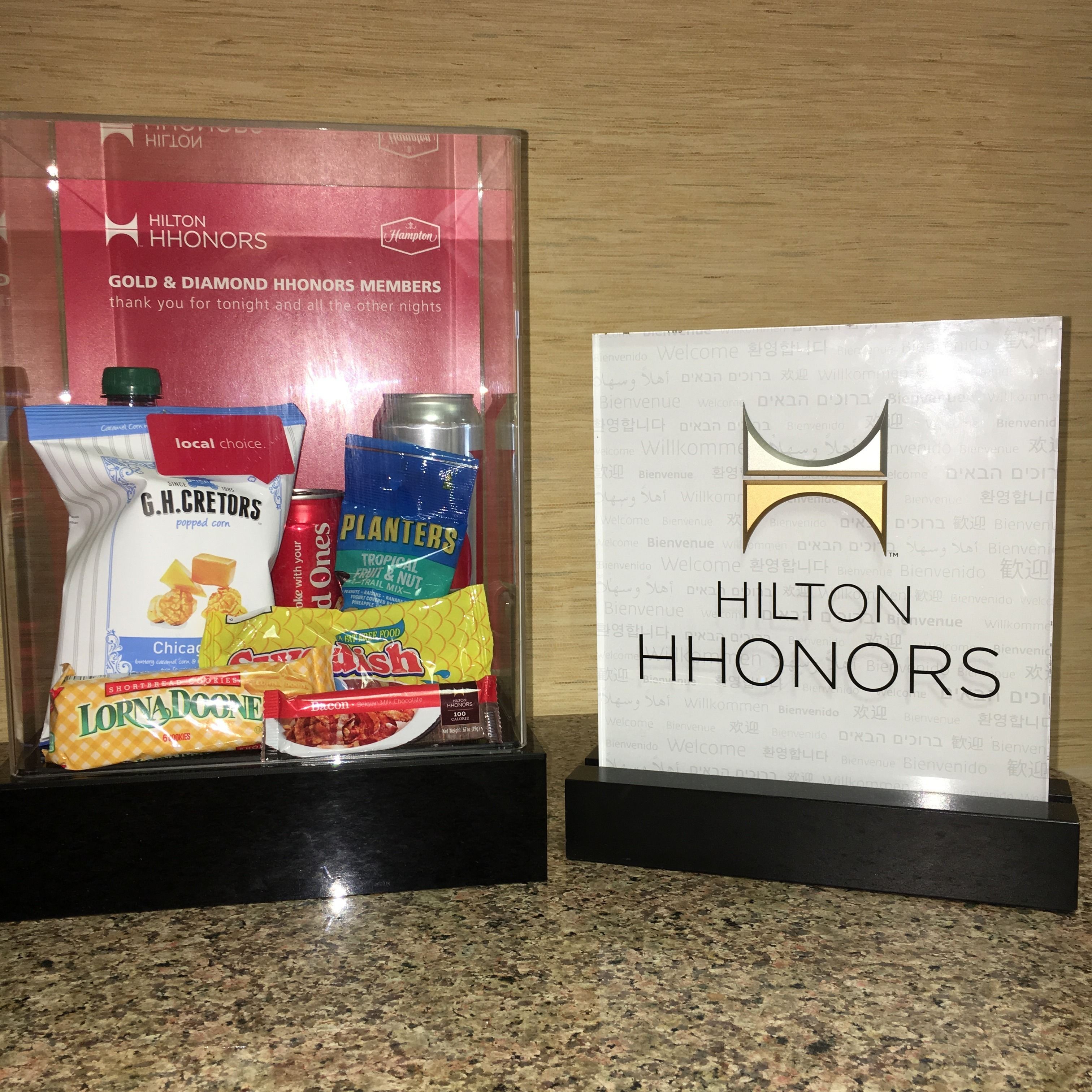 Exposição de presentes Hilton HHONORS, incluindo lanches e bebidas.