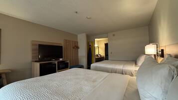 Quarto de hotel com duas camas, televisão, escrivaninha e espelho.