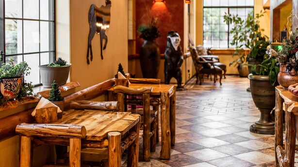 Um interior rústico com bancos de madeira, um candelabro e uma decoração de parede com tema de veado.