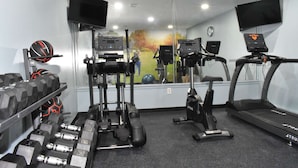 Uma academia com esteiras, bicicleta ergométrica e equipamentos de musculação.