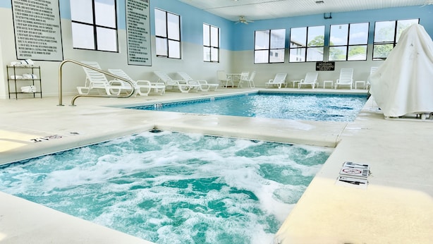 Piscina interna com várias pistas, cadeiras de descanso e área coberta.
