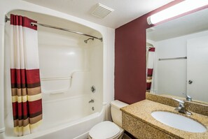 Casa de banho com banheira, sanita, lavatório e espelho.