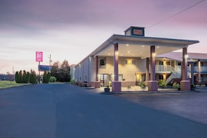 Um motel com área de estacionamento coberta, entrada visível e placa indicativa do Red Roof Inn & Suites.