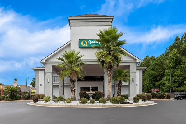 Entrada de hotel com uma placa indicando "Quality Inn by Choice Hotels".