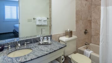 Casa de banho com duas pias, sanita, banheira e cortina de chuveiro.