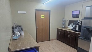 Cozinha compacta com porta de armazenamento, máquina de café e geladeira.