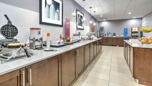 Cozinha moderna com máquina de waffles, espaço para café e exposição de frutas.