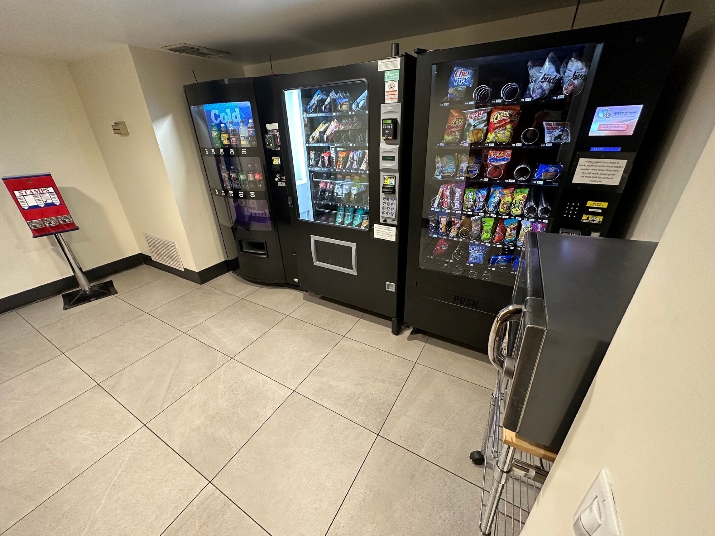 Uma fileira de máquinas de venda automática em um espaço comercial com piso de azulejos.