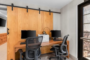Um espaço de trabalho com dois monitores, uma impressora e duas cadeiras de escritório.