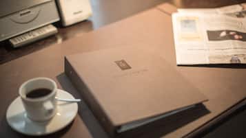 Uma mesa com uma xícara de café, um livro e um jornal.