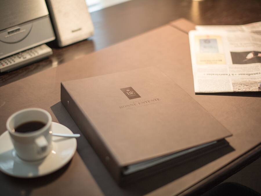 Uma mesa com uma xícara de café, um livro e um jornal.