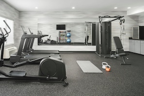 Uma academia moderna em casa, com esteiras, um banco de musculação e equipamentos de exercício.