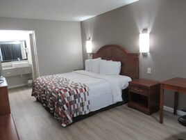 Quarto de hotel com cama, mesa de cabeceira e janela com cortinas.