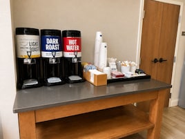 Uma estação de café com três dispensadores rotulados 'Torra Clara', 'Torra Escura' e 'Água Quente'.