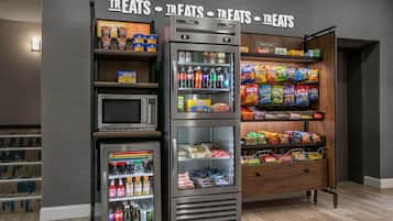 Área de máquinas de venda automática com lanches, bebidas e micro-ondas.