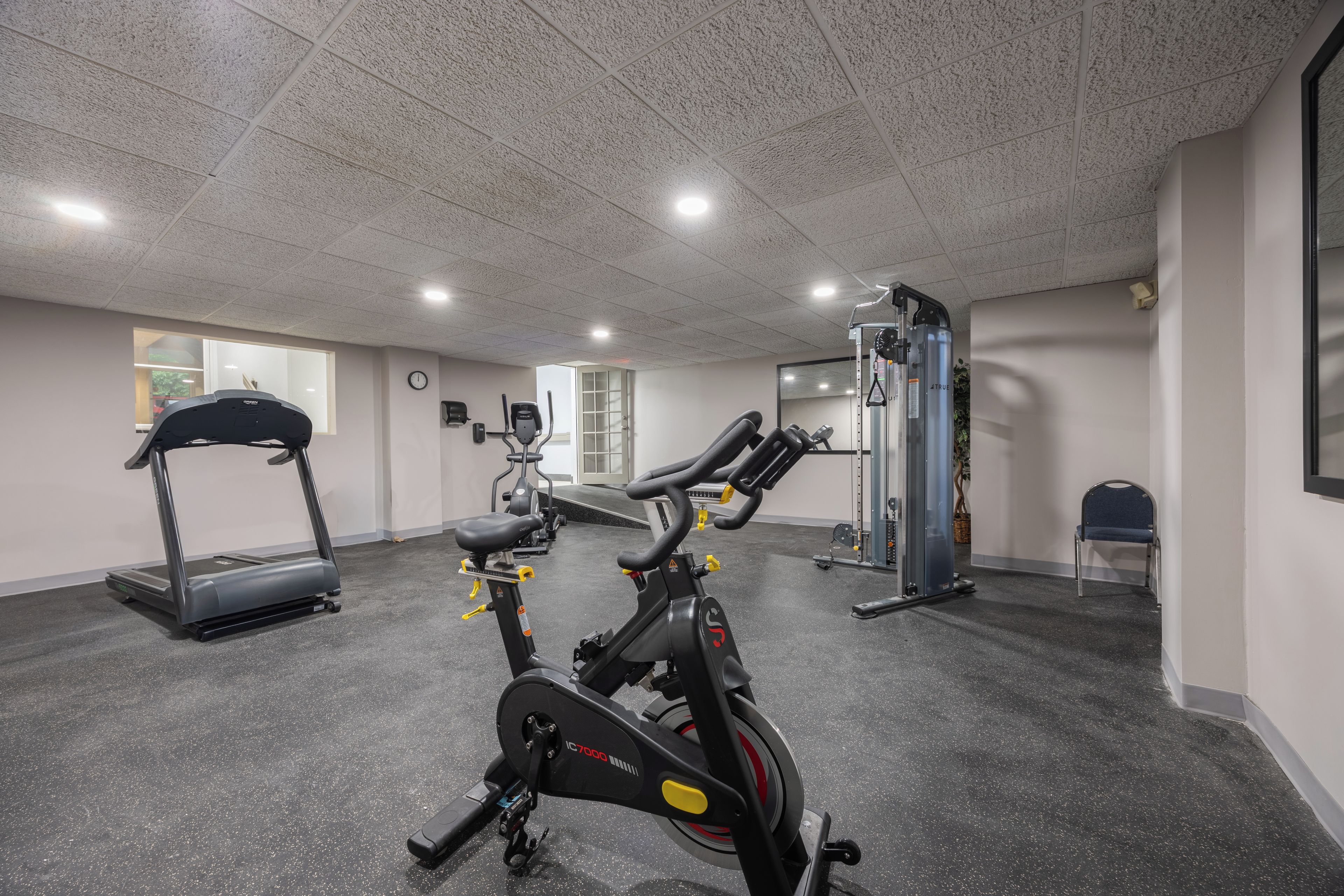Academia com máquinas de cardio, equipamentos de musculação e um espelho grande.