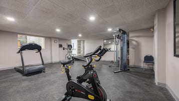 Academia com máquinas de cardio, equipamentos de musculação e um espelho grande.