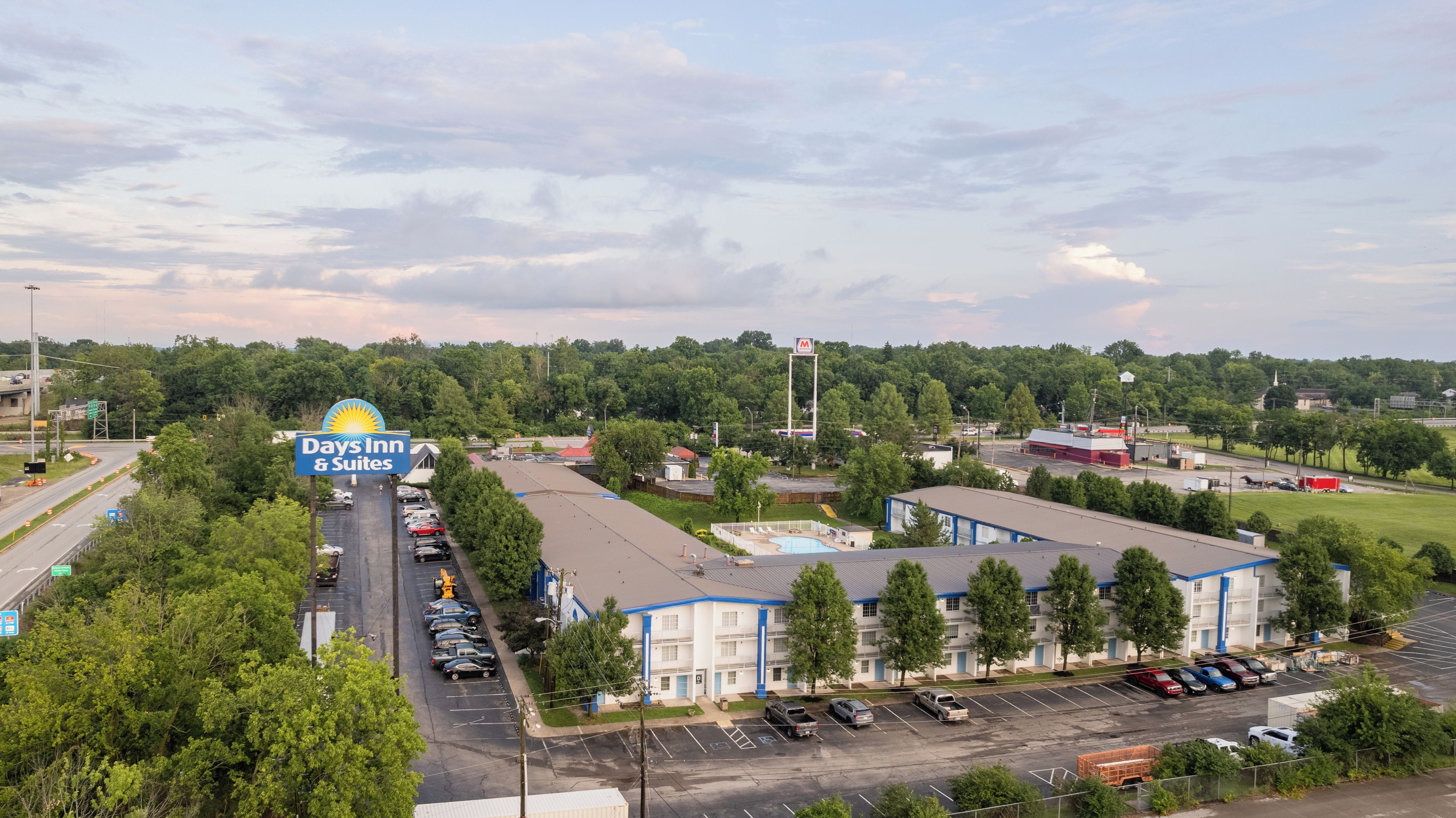 Um Days Inn & Suites com estacionamento, piscina e um edifício grande em esquema de cores azul e branco.