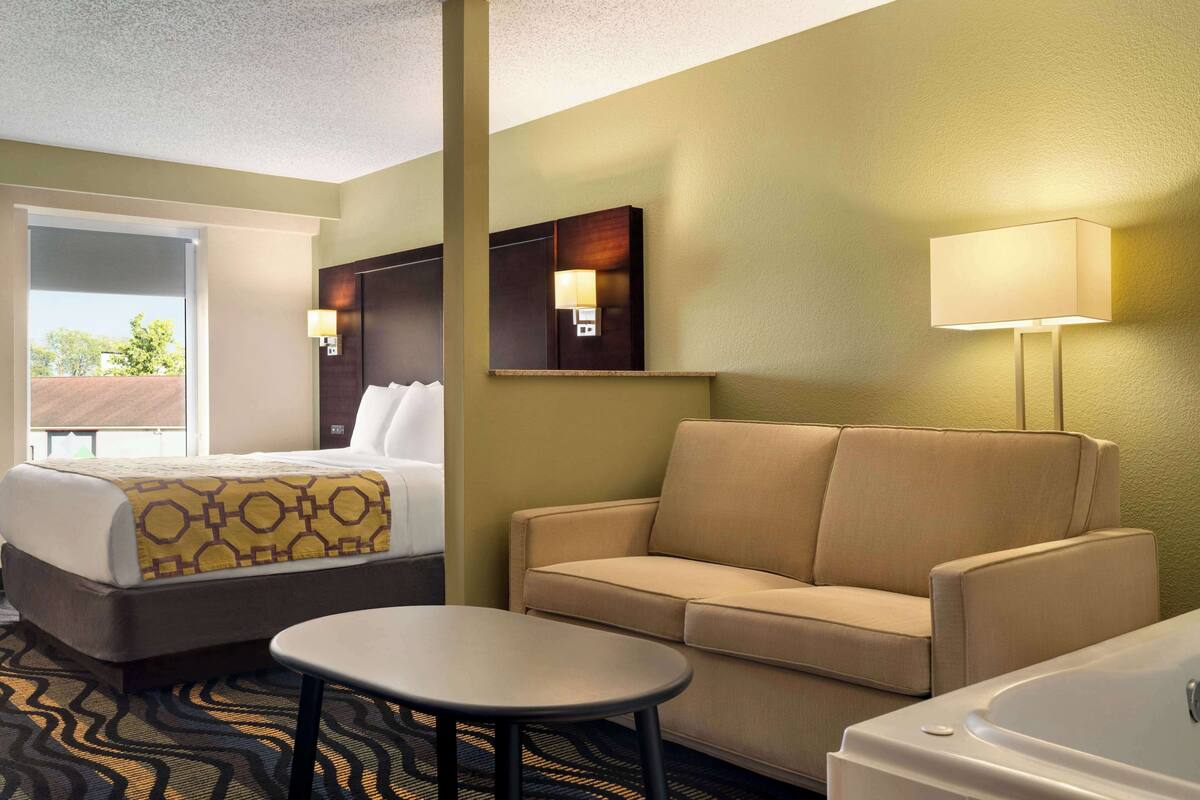 Quarto de hotel com uma cama, um sofá, uma mesinha e uma banheira.