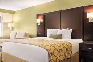 Quarto de hotel com uma cama grande, duas mesas de cabeceira, uma cadeira e um abajur.