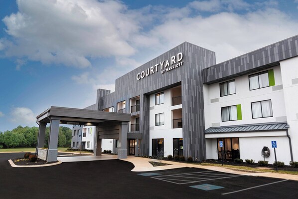 Um hotel Courtyard by Marriott com entrada coberta, vários andares e estacionamento.