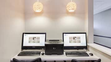 Um espaço de trabalho com dois computadores portáteis, uma impressora e duas cadeiras.