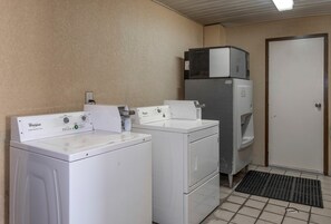 Uma lavanderia com duas máquinas de lavar Whirlpool e uma geladeira empilhada.