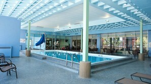 Piscina interna com área coberta, equipamentos de ginástica e assentos.