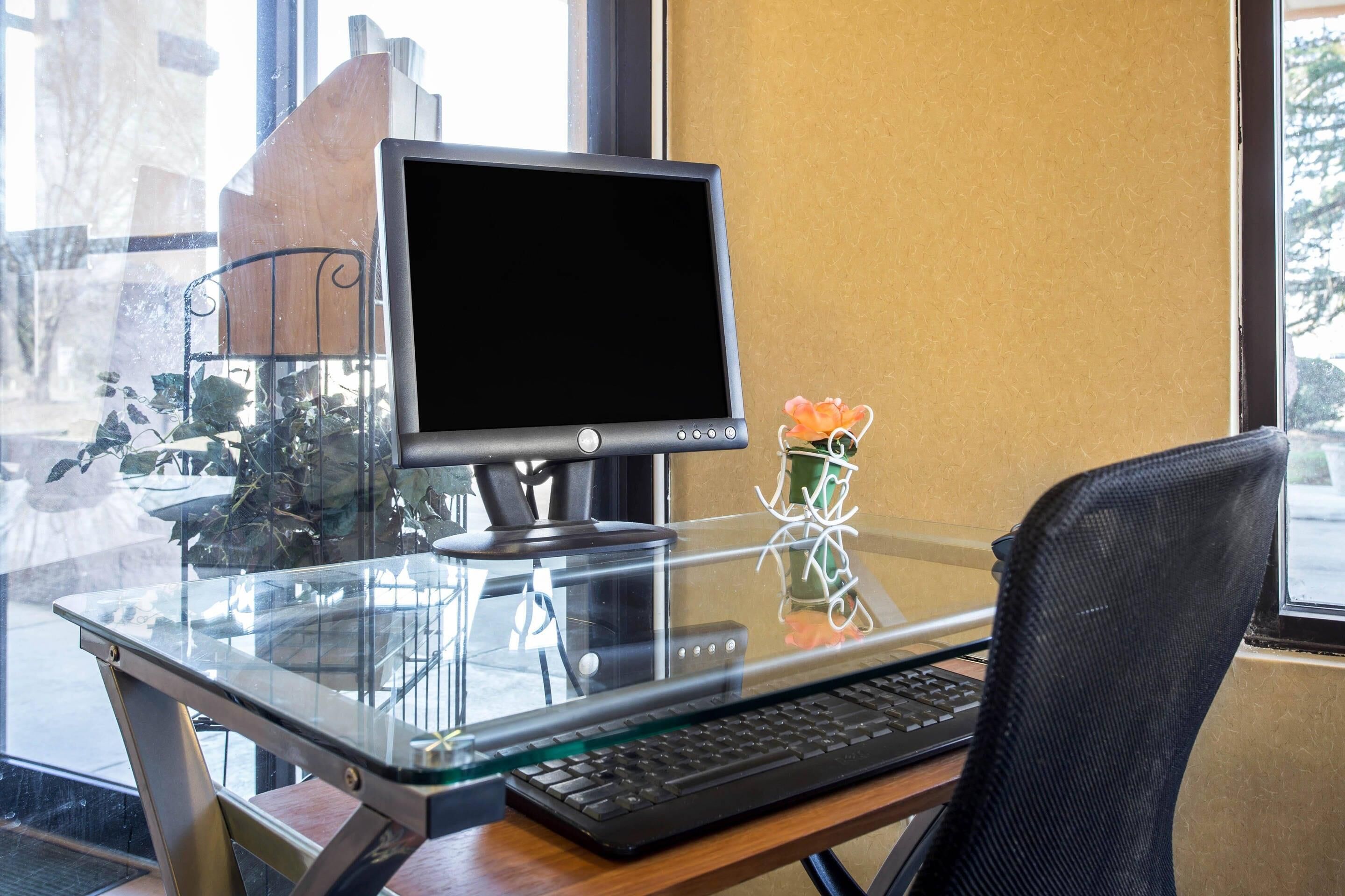 Uma mesa de escritório moderna com monitor de computador, teclado e cadeira.