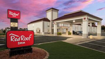 Red Roof Inn com placa anunciando quartos novos e café da manhã quente.