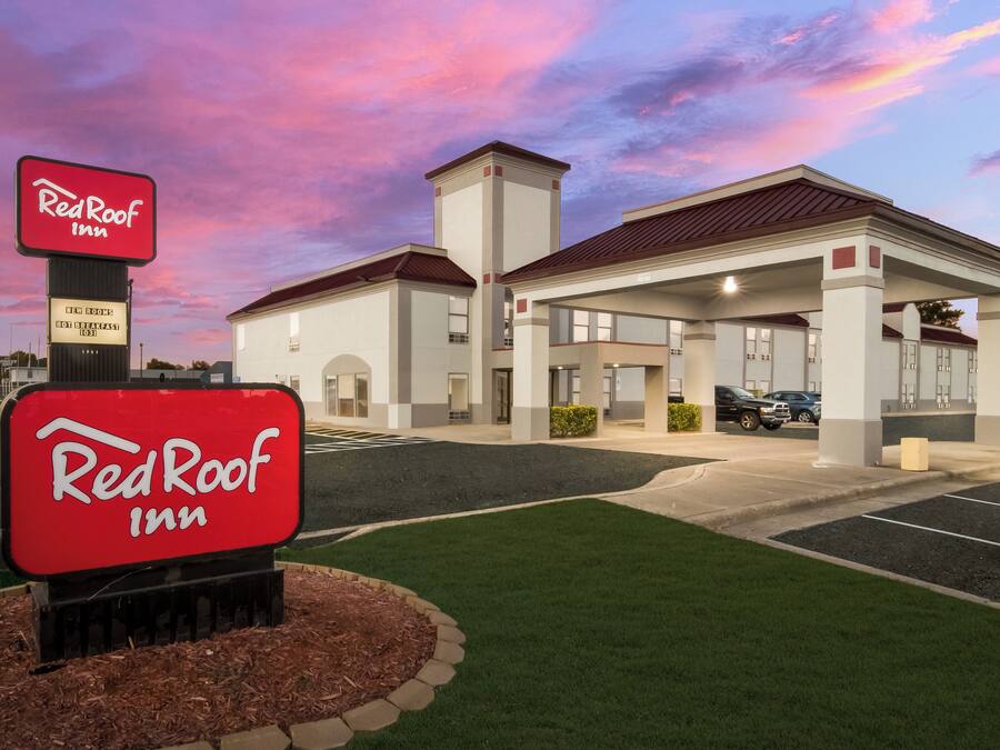 Red Roof Inn com placa anunciando quartos novos e café da manhã quente.
