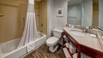 Casa de banho com banheira, sanita e toucador com espelho.