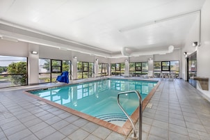 Piscina interior com paredes de vidro transparente, chão ladrilhado e capa azul.