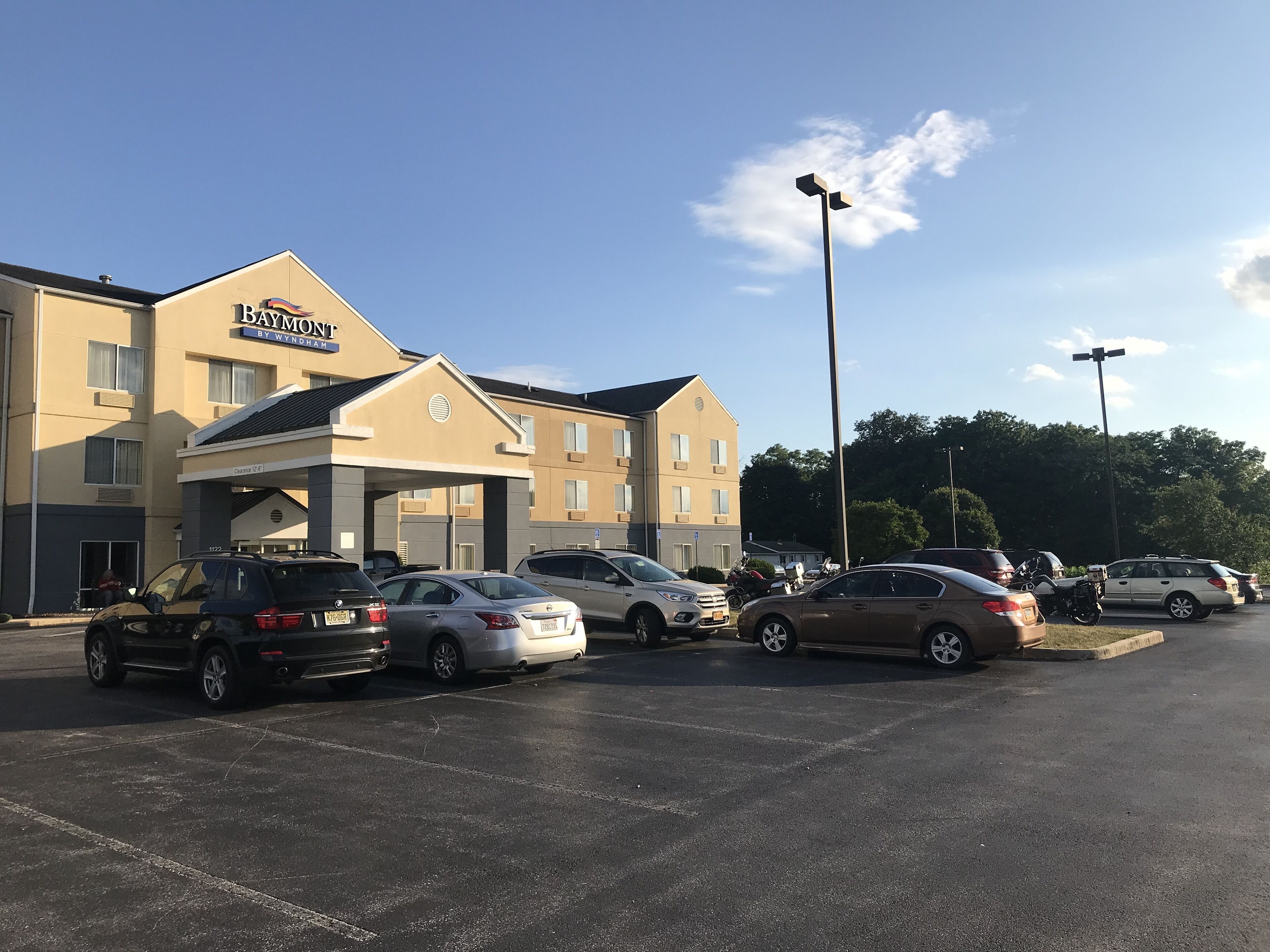 Hotel com estacionamento, vários carros e céu limpo.