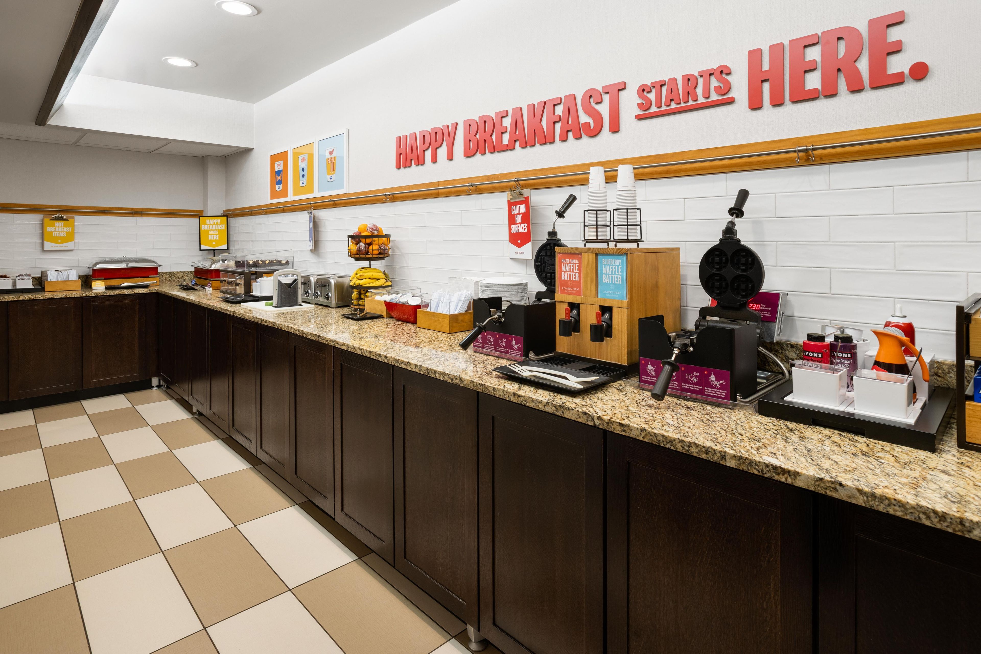 Uma área de café da manhã com uma placa que diz 'HAPPY BREAKFAST STARTS HERE'.