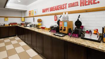 Uma área de café da manhã com uma placa que diz 'HAPPY BREAKFAST STARTS HERE'.