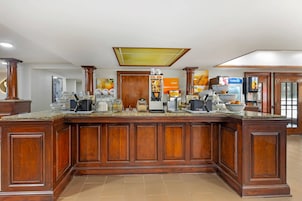 Uma grande ilha de cozinha de madeira com um espaço para café, micro-ondas e frigorífico.