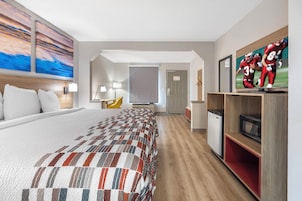 Quarto de hotel com uma cama grande, televisão, escrivaninha e guarda-roupa.