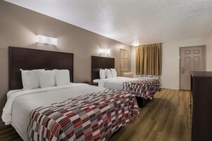 Quarto de hotel com duas camas, um guarda-roupa, uma casa de banho e uma porta.