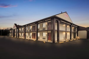 Um hotel com vários quartos, área externa coberta e estacionamento.