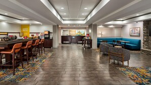 Um hall de hotel com área de bar, assentos e balcão de recepção.