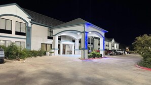 Uma entrada de hotel moderna com galeria coberta e área de estacionamento.