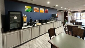 Uma área de pequeno-almoço moderna com serviço de buffet, lugares para sentar e vista para o exterior.